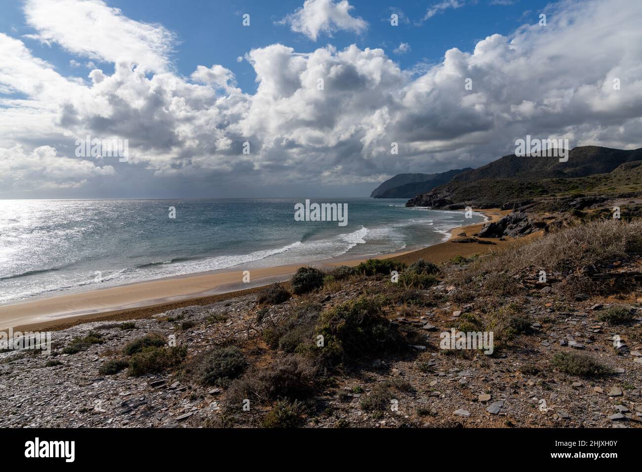 a rocky ocean coast with mountains and a beautiful golden sand beach in ...