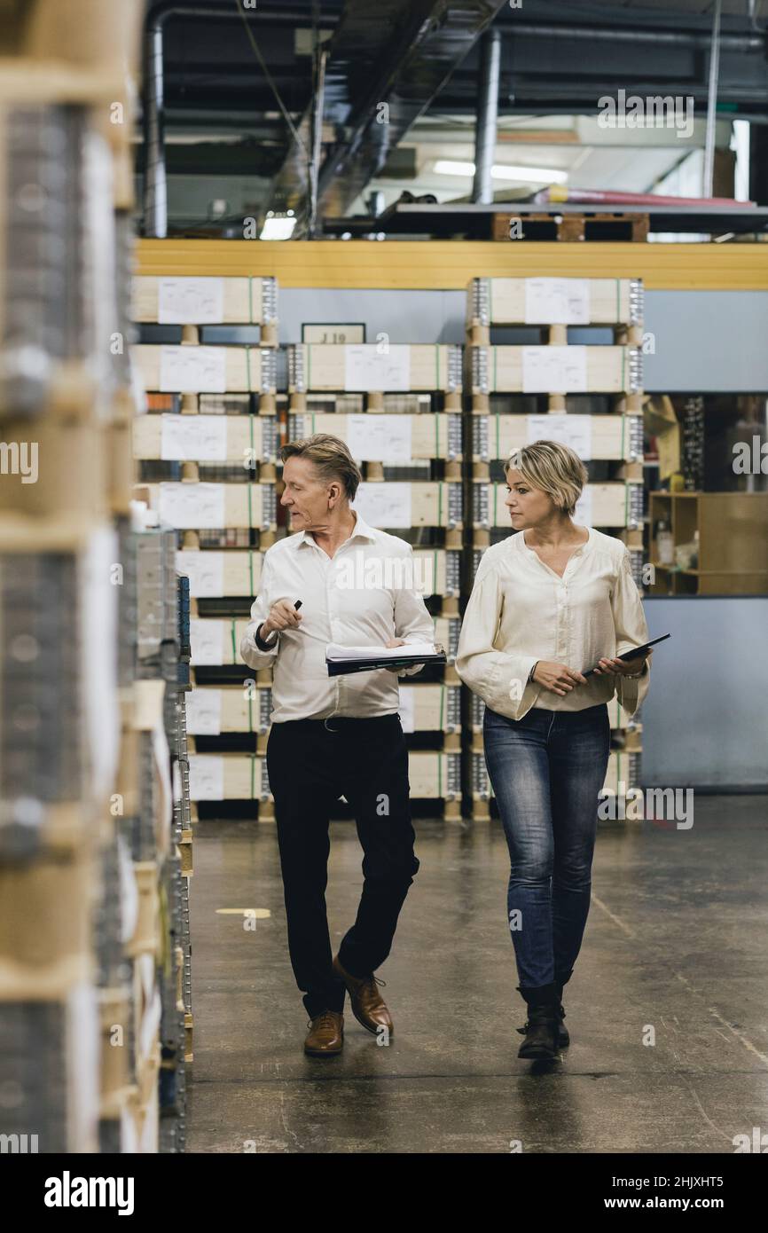 Businessman and female manager walking in factory warehouse Stock Photo ...