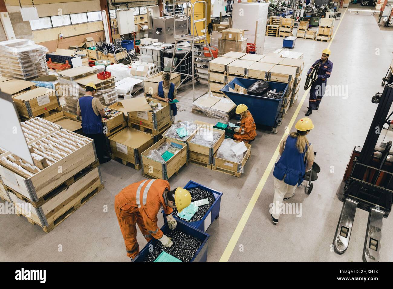 Male and female blue-collar workers in uniform working in factory ...