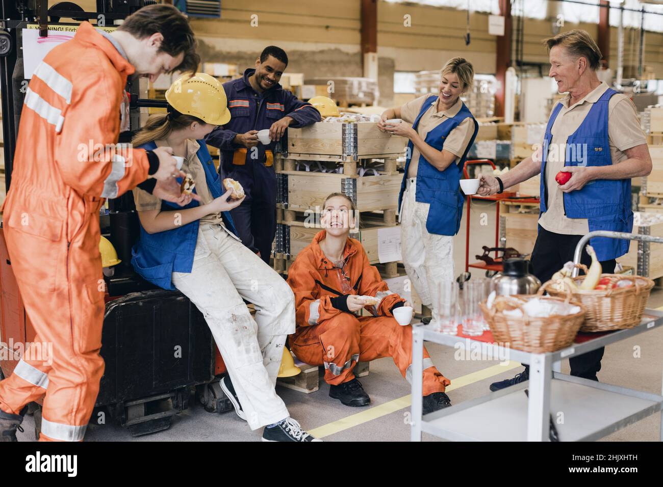 Happy male and female workers having snacks in warehouse Stock Photo ...