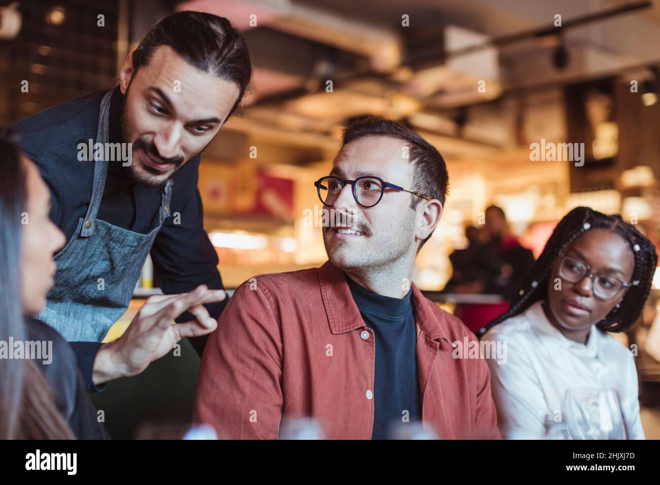 Waiter talking with friends in restaurant during dinner Stock Photo - Alamy