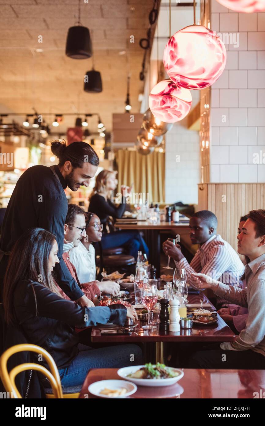 Male waiter serving food to customers in restaurant Stock Photo - Alamy