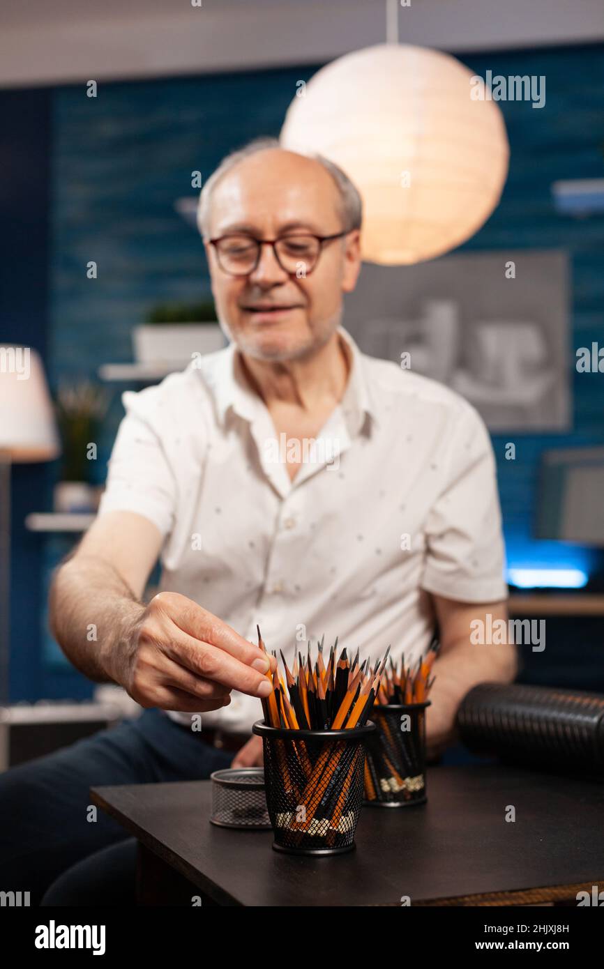 Selctive focus on elderly man illustrator selecting sharp hb pencil to ...