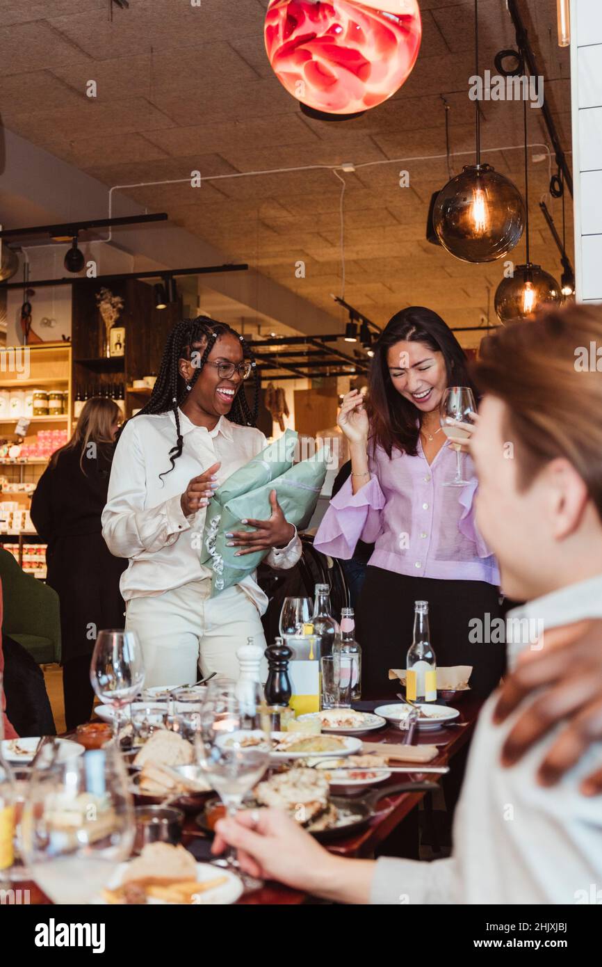 Multiracial female friends laughing while celebrating during dinner ...