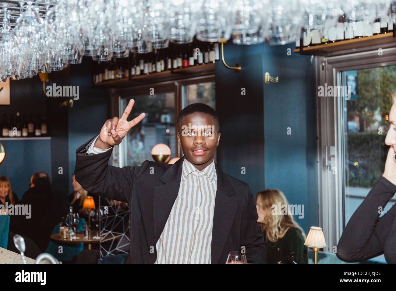 Portrait of man doing peace sign in bar Stock Photo - Alamy