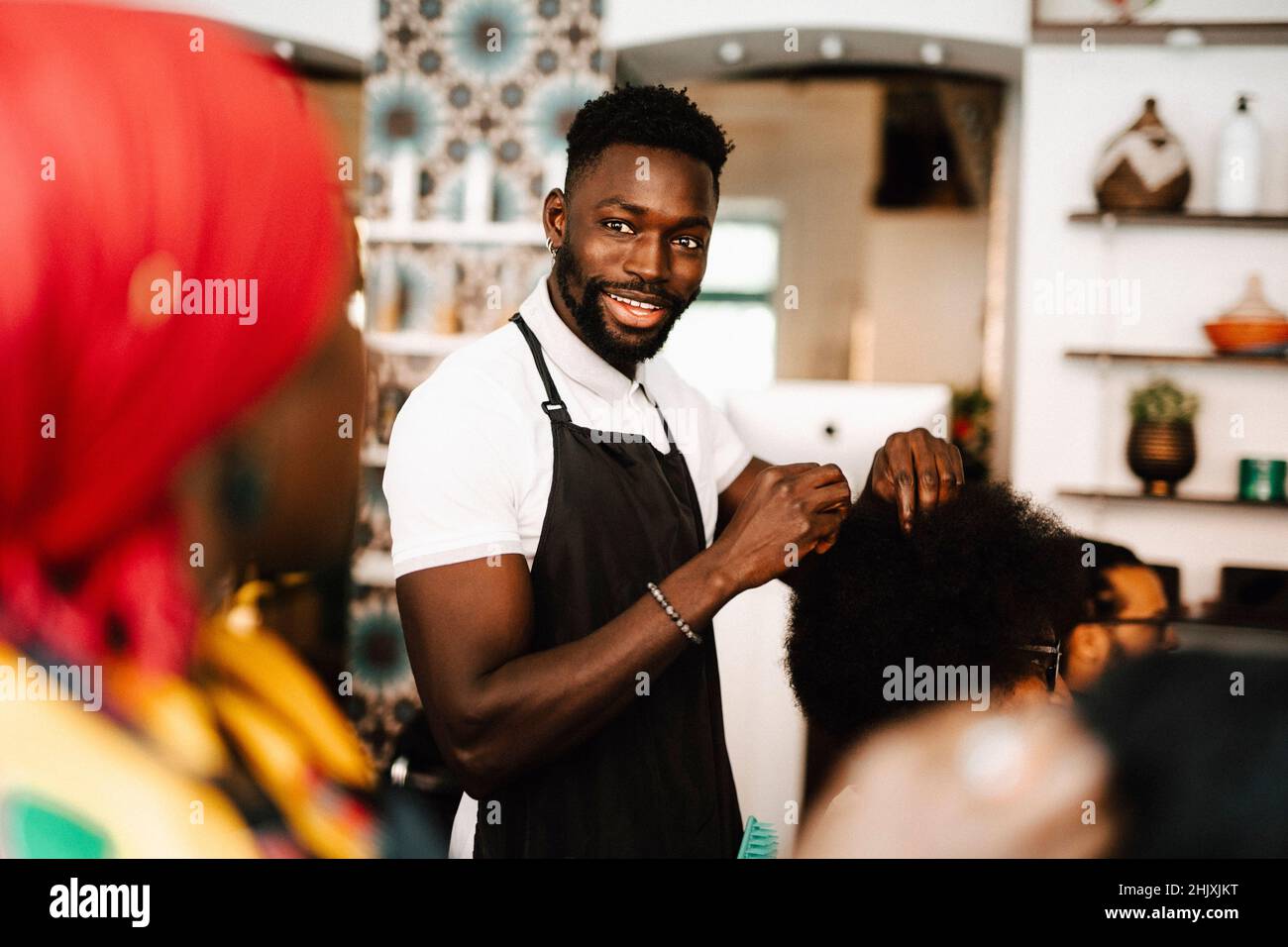 Smiling male hairdresser talking with female coworker in barber shop ...