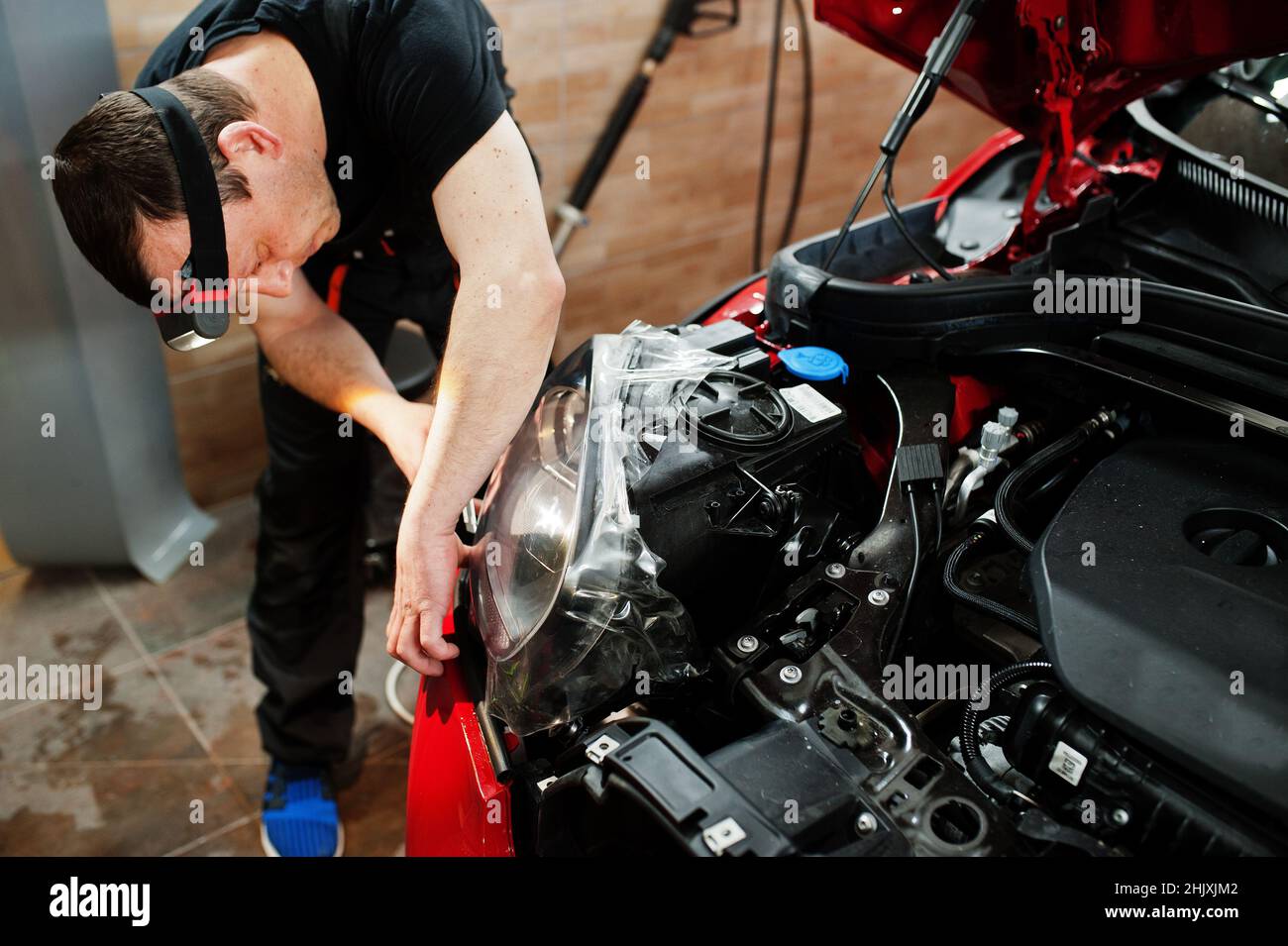 Car service worker put anti gravel film on a red car body at the ...