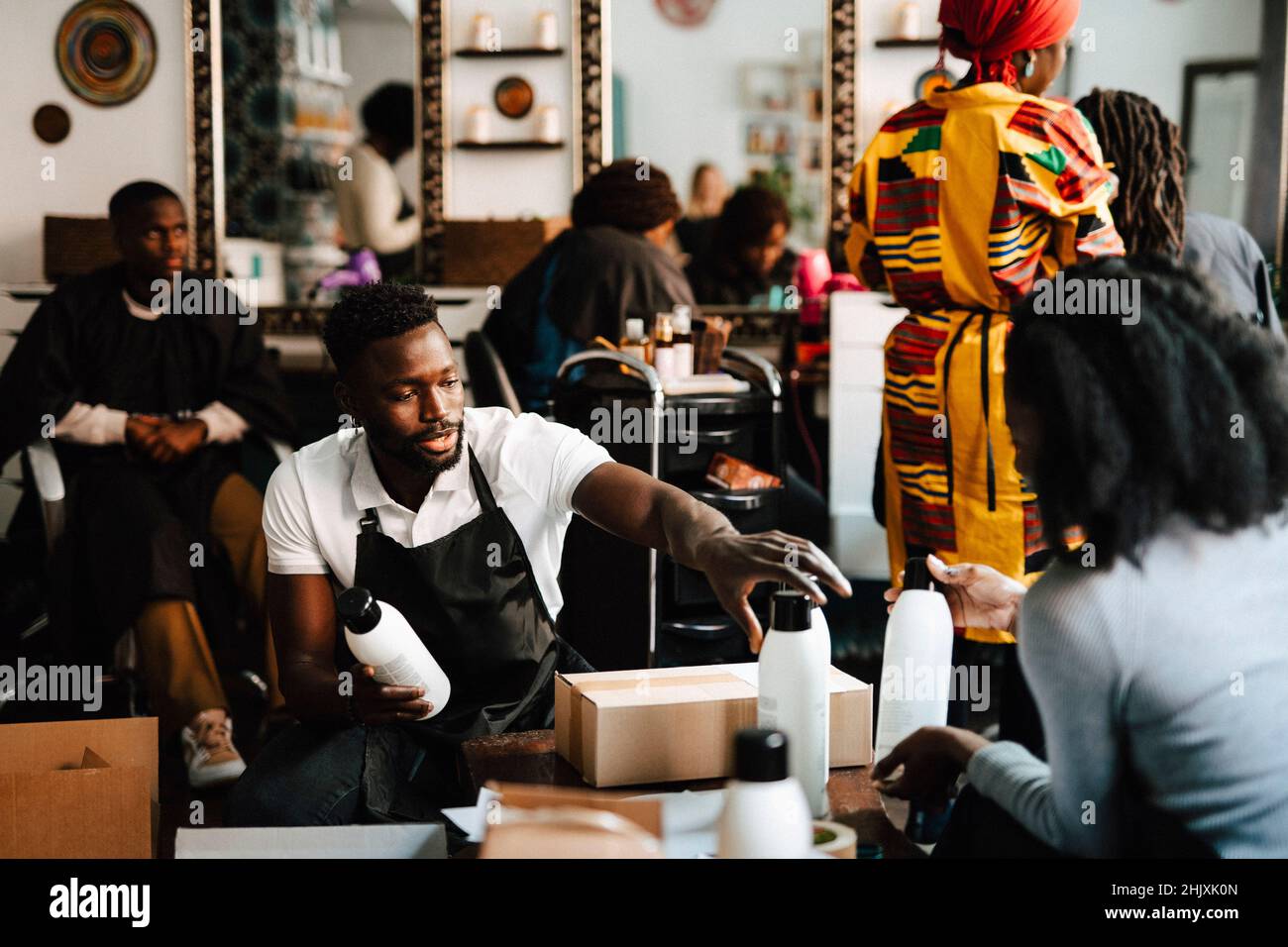 Male hairdresser discussing with female coworker in barber shop Stock ...