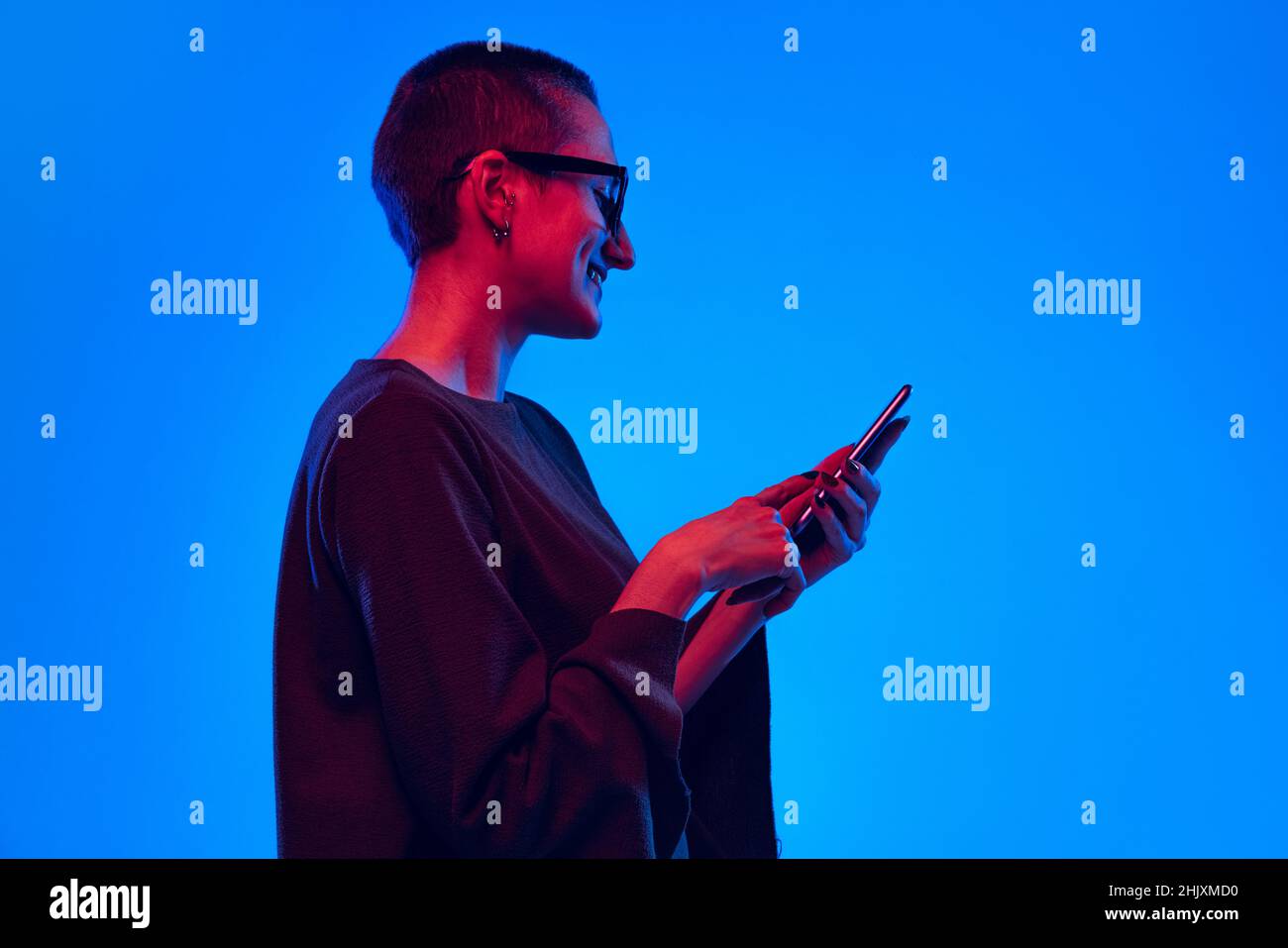 Side view of emotional young girl with hairdo buzzcut using phone ...