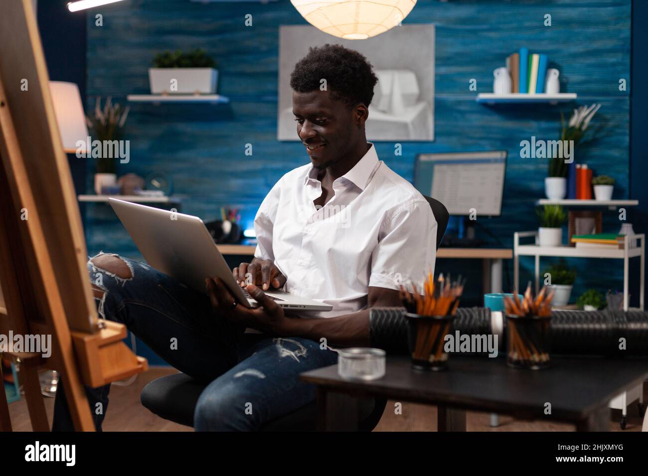 Young artist holding laptop computer searching for draw inspiration ...