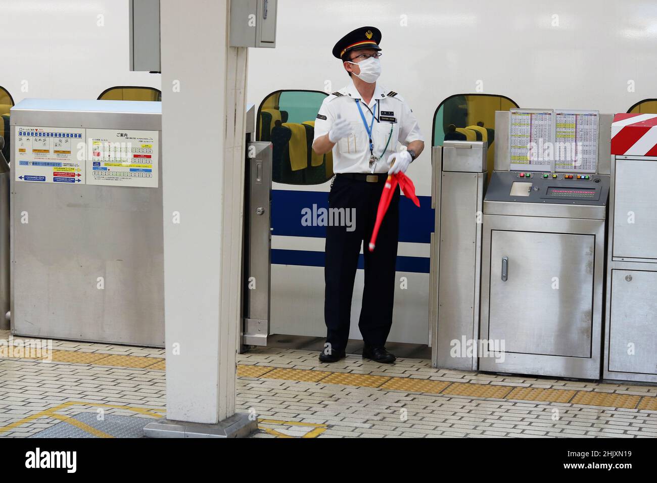 TOKYO, JAPAN - September 29, 2021: A station worker with a flag on a ...
