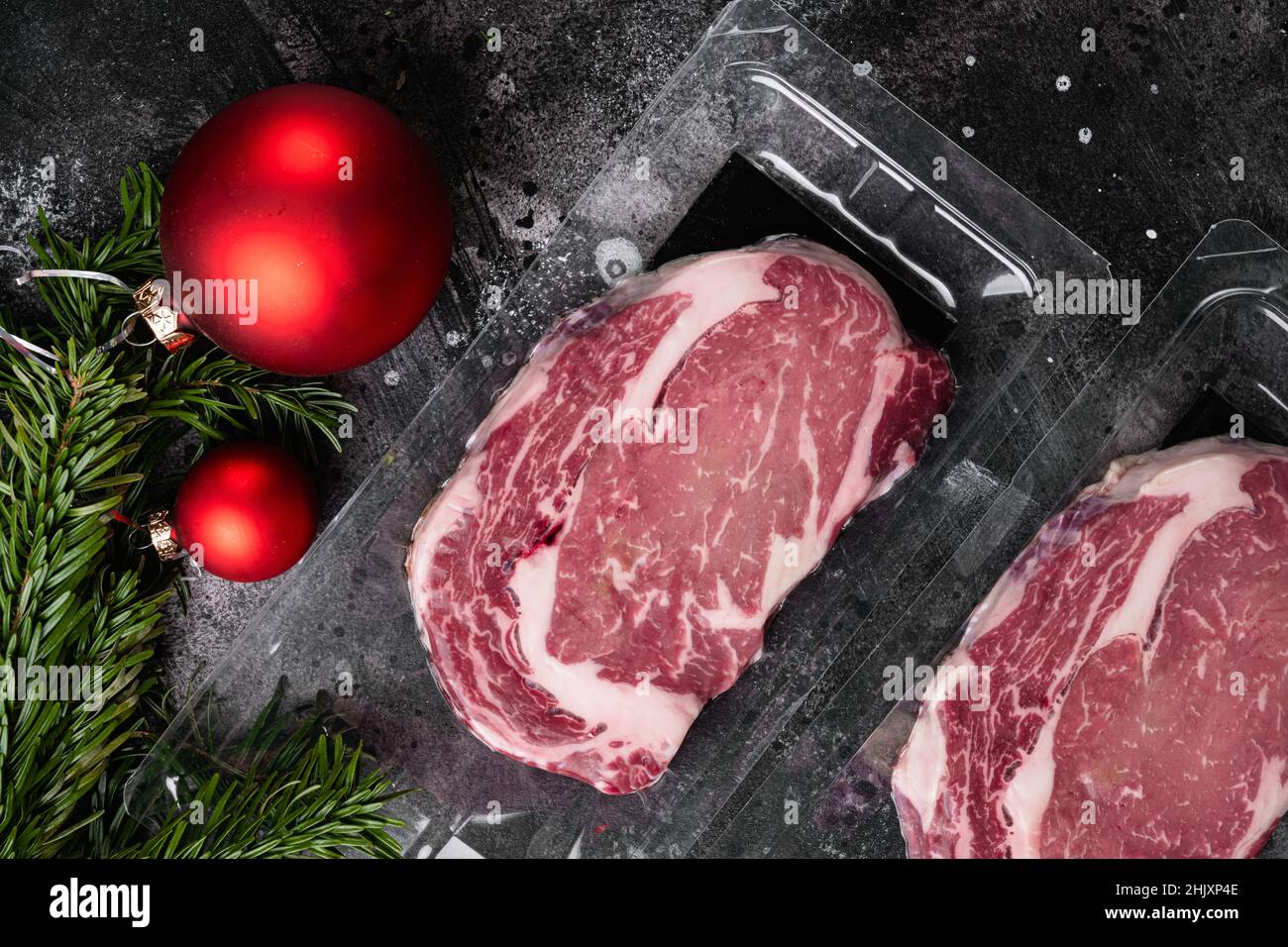 Rib eye steak pack with a Christmas tree set, on black dark stone table ...