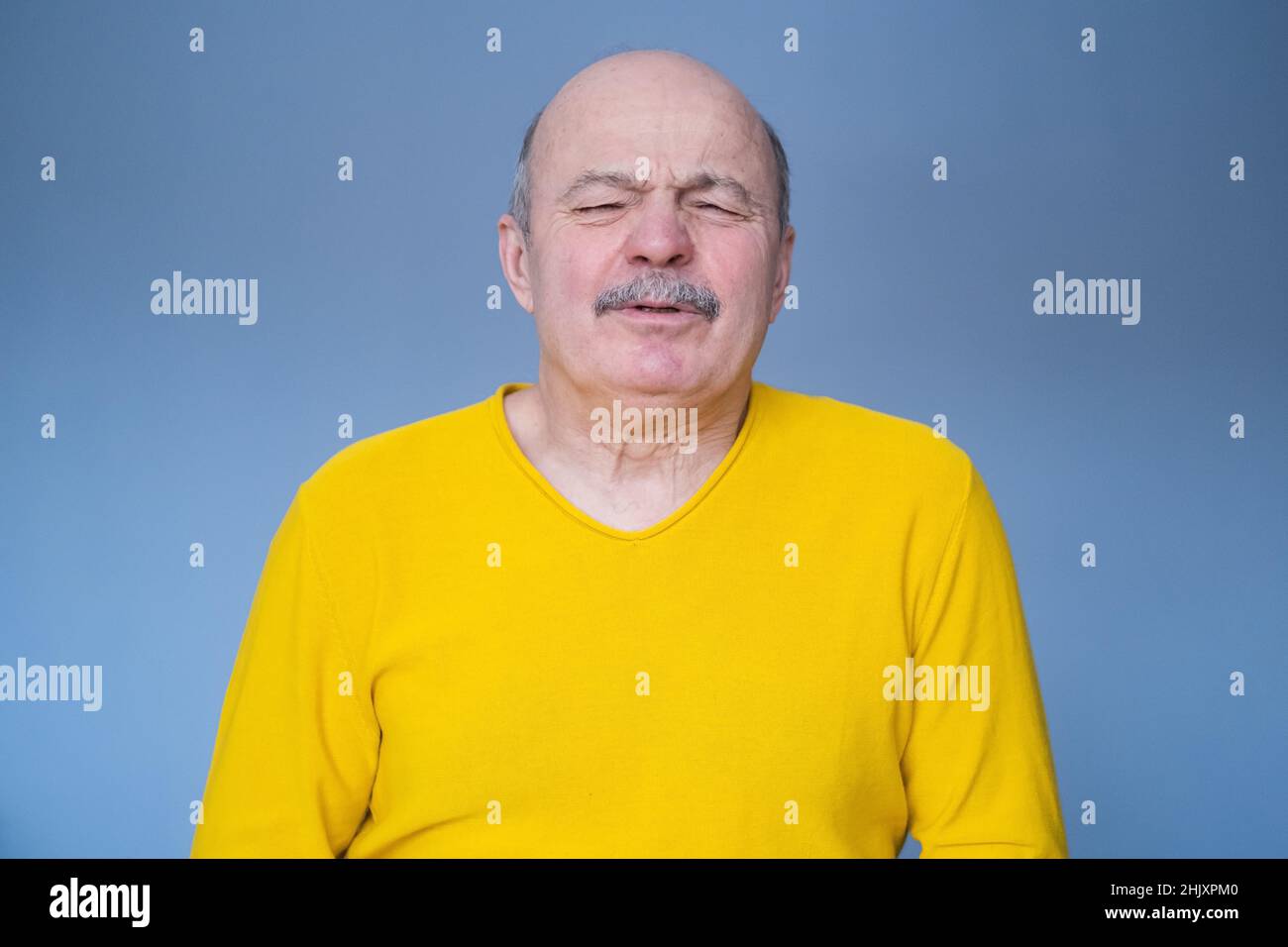 Hispanic old man suffering from pain, isolated on blue wall Stock Photo ...