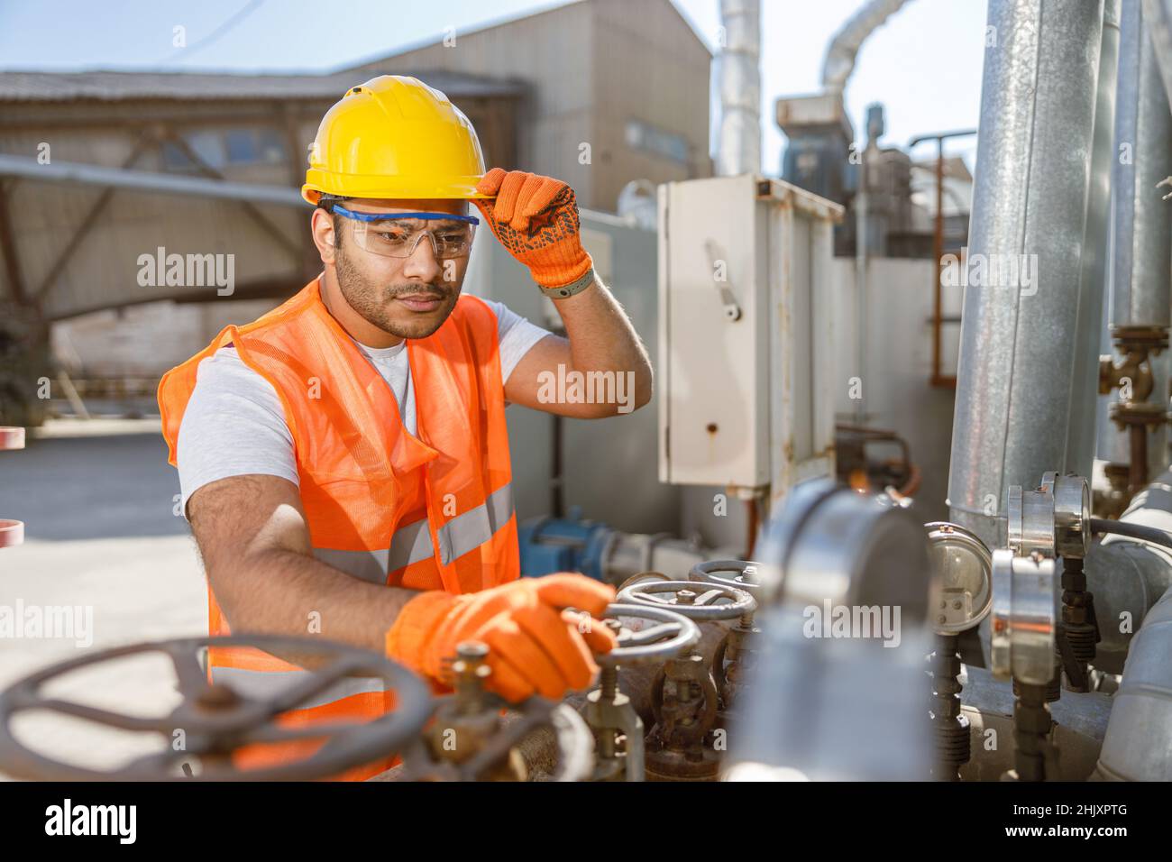 Worker with safety equipment working at construction plant Stock Photo ...