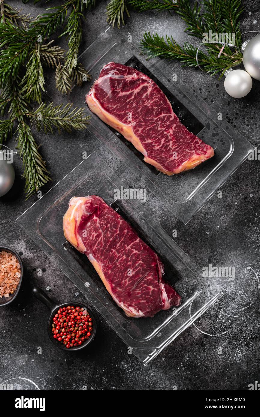 Vacuum packed New-York steak with a Christmas tree set, on black dark ...