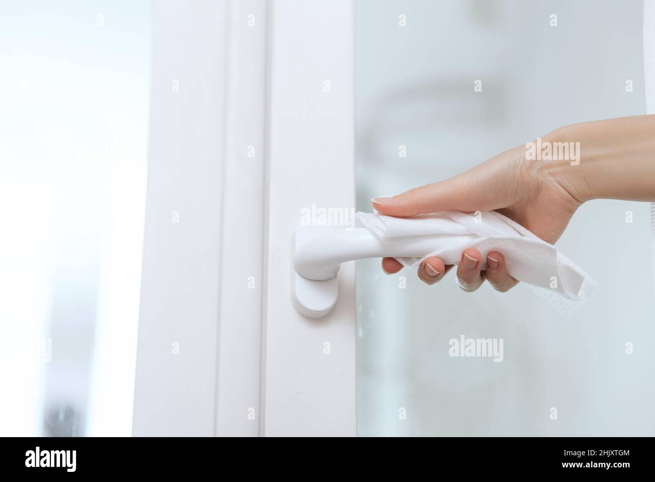 Cleaning door handles with an antiseptic wet wipe and gloves. Woman ...