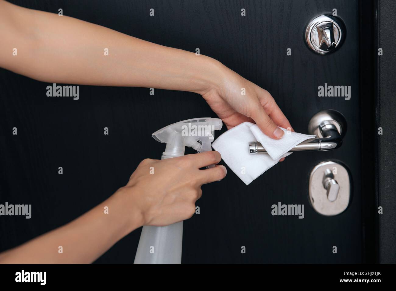 Cleaning black door handles with an antiseptic wet wipe. Woman hand ...