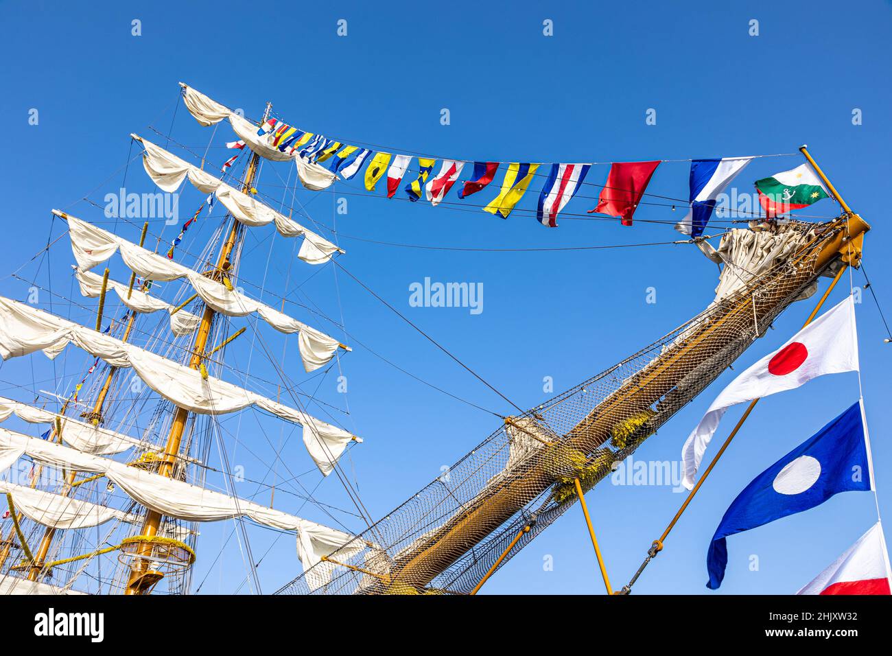 A low angle shot of a white tall ship with different flags against a ...