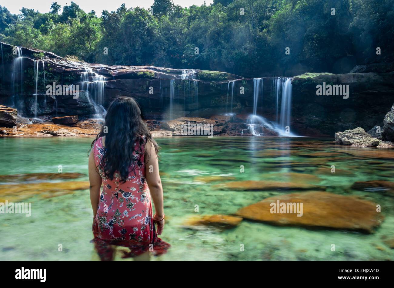 girl standing with waterfall flowing streams and calm blurred clear ...