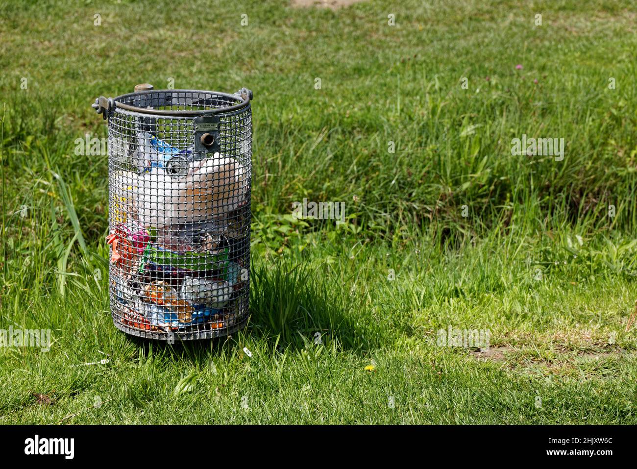 lattice trash can with a lot of garbage in the bucket, in the ...