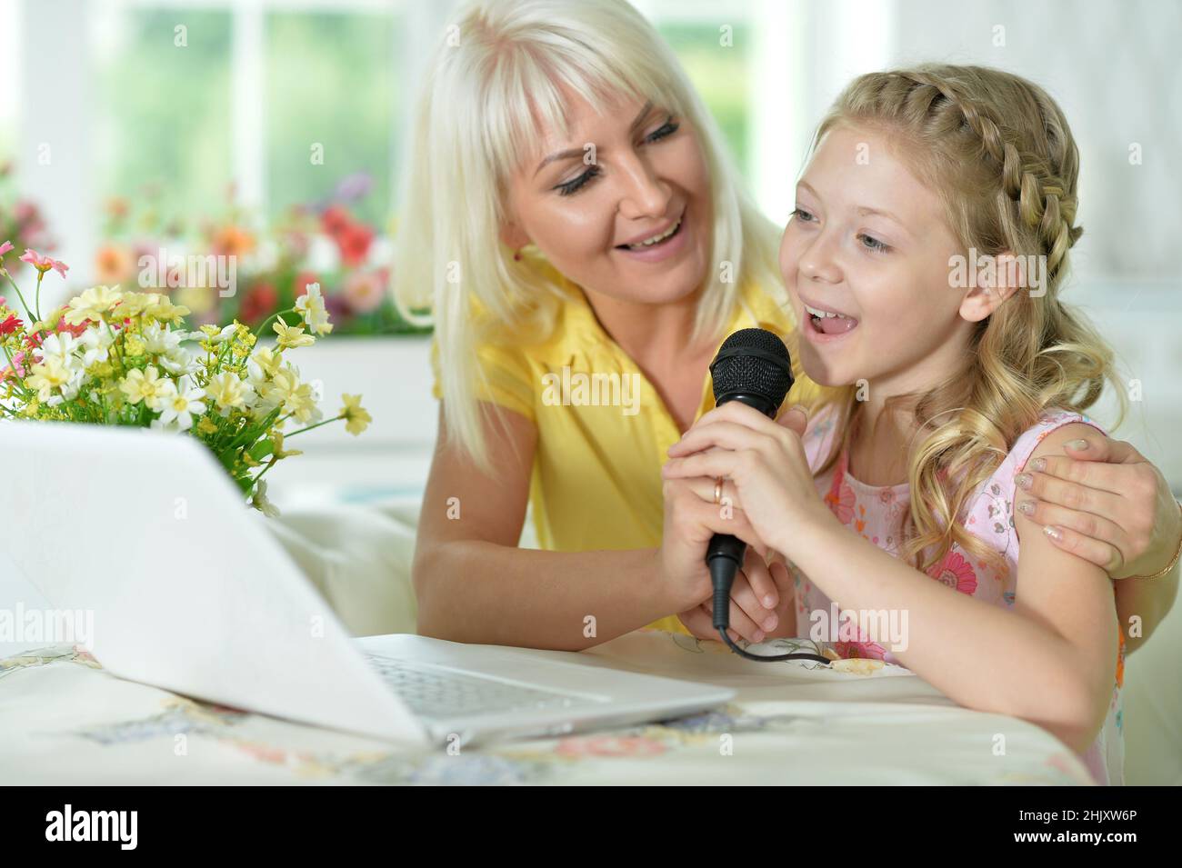 Beautiful woman with her daughter at home singing karaoke Stock Photo ...