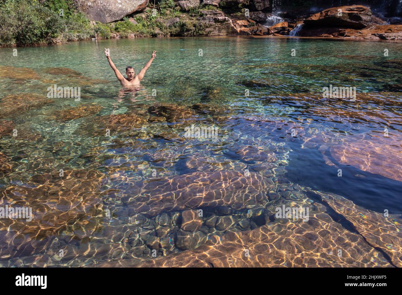 young man standing in flowing river clear water at morning from flat ...