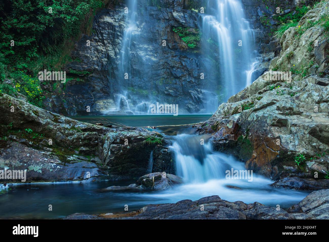 waterfall flowing streams through rocks with calm blurred water surface ...