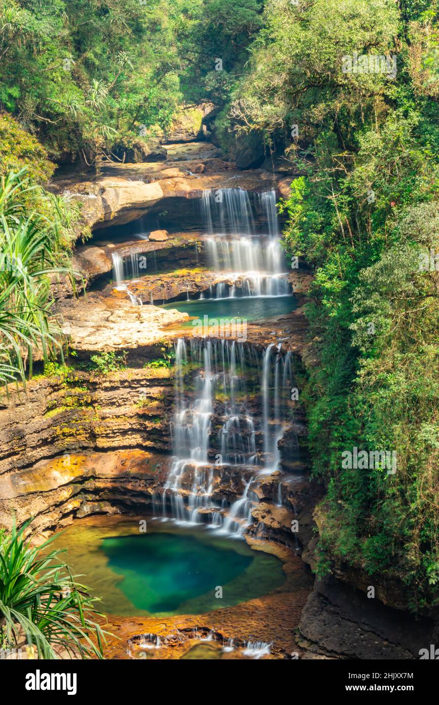 two layered waterfall falling from mountain top in deep green forests ...