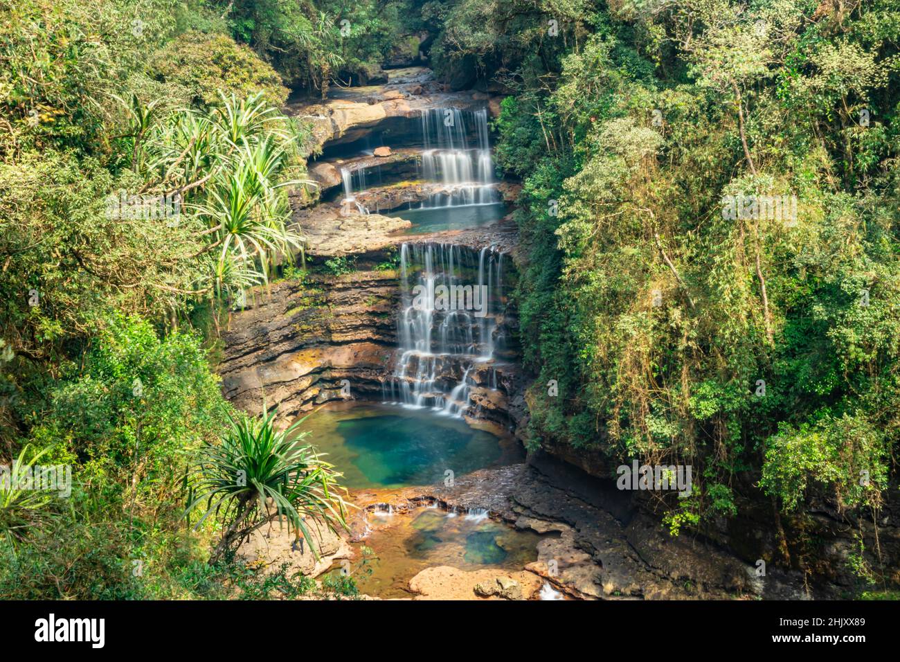 two layered waterfall falling from mountain top in deep green forests ...