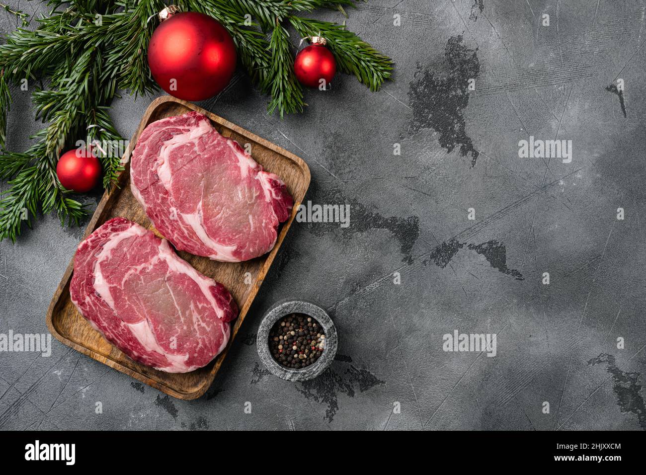 Fresh raw rib-eye steak with a Christmas tree set, on gray stone table ...