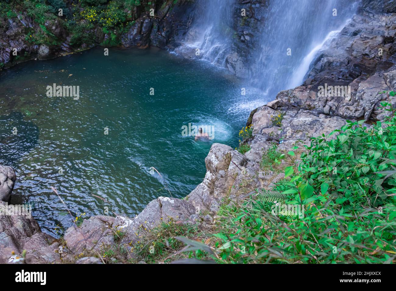 young man swimming at natural waterfall blue water at morning from top ...