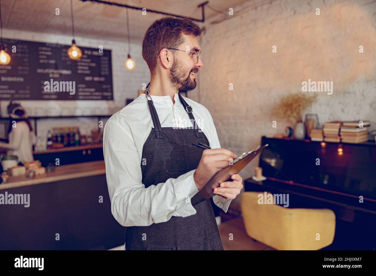Joyful male worker writing on clipboard in cafe Stock Photo - Alamy