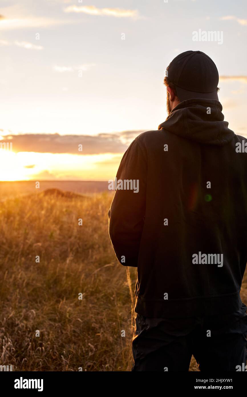 View from back on unrecognizable male looking at sunset, in ...