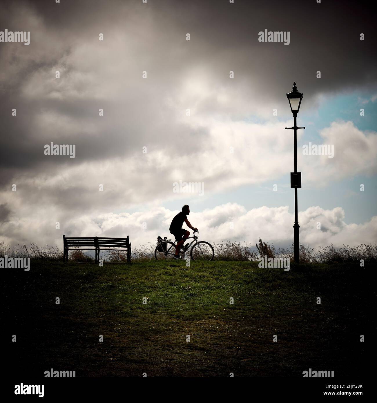 Cyclist on Lytham seafront riding past bench and lamp post Stock Photo ...