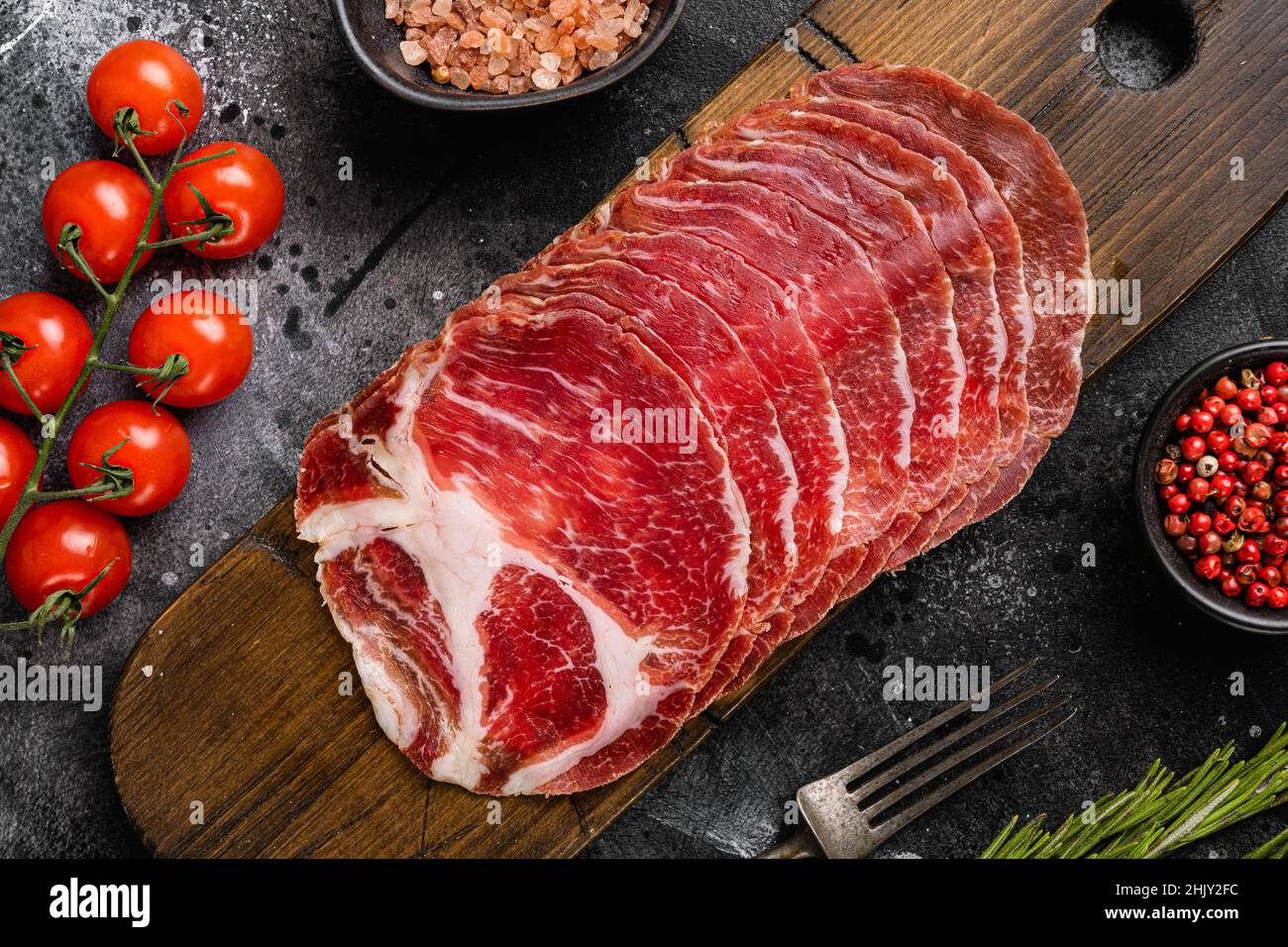 Italian sliced cured coppa meat set, on black dark stone table ...