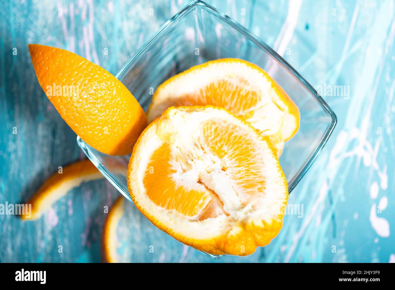 Top view of a halved unpeeled orange in a glass bowl on the blue ...