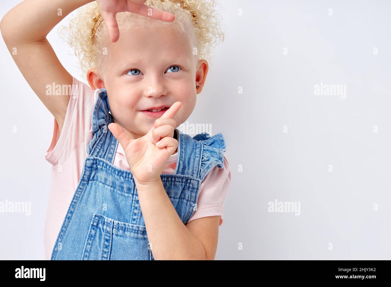 Portrait of small girl making frame with hands and fingers with happy ...