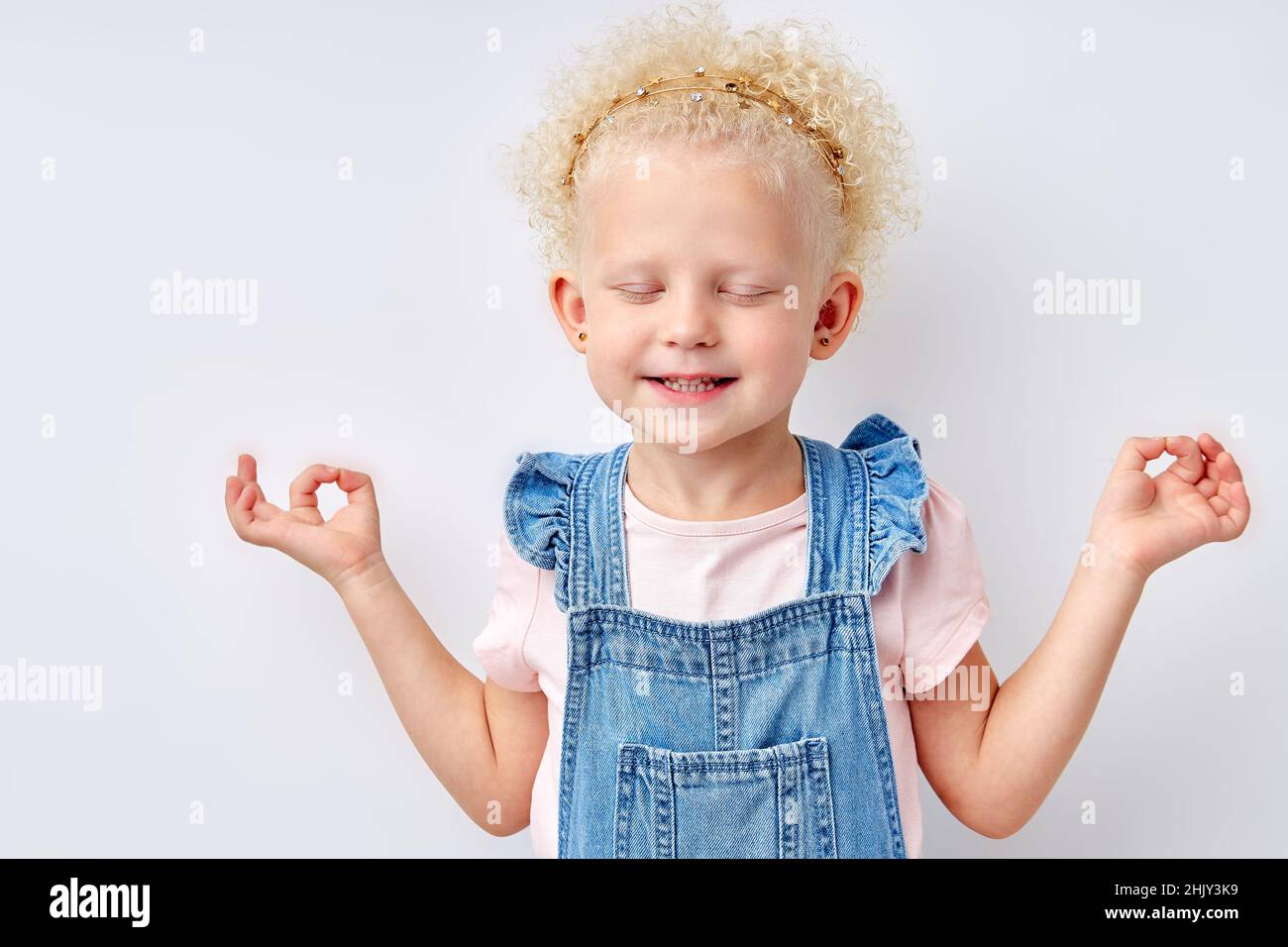 smiling child girl meditating isolated on white studio background. cute ...