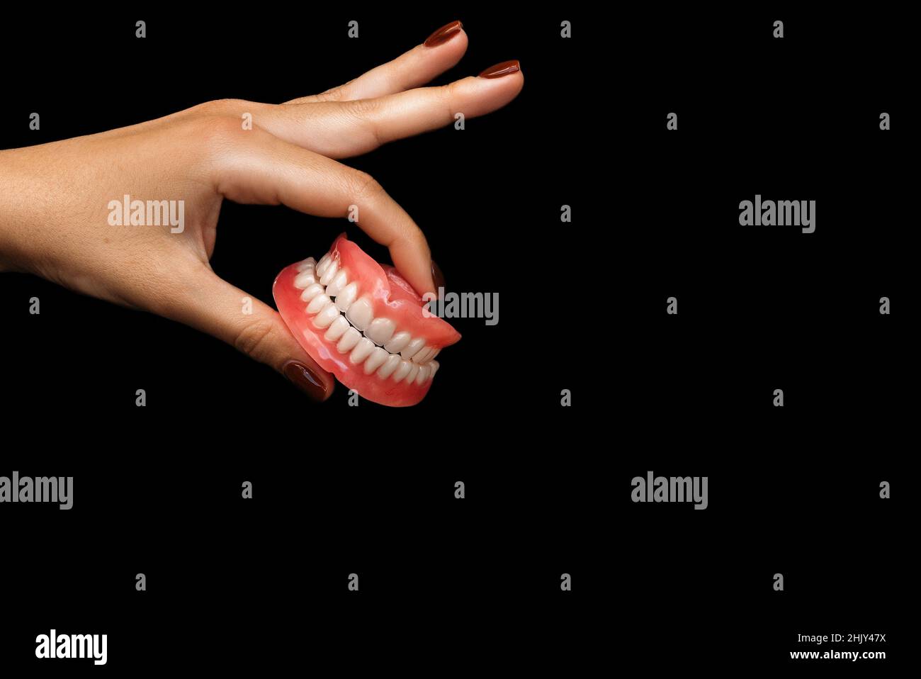 Denture in hand. False teeth in the hand. Denture on a black background ...