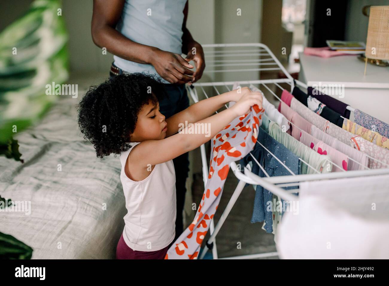 Daughter arranging clothes on drying stand at home Stock Photo - Alamy