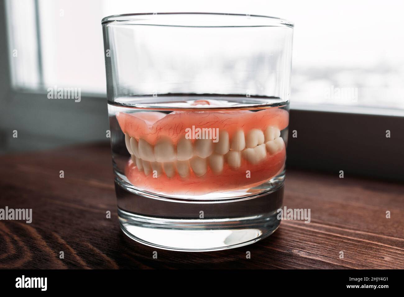 A denture in a glass of water. Dental prosthesis care. Full removable ...