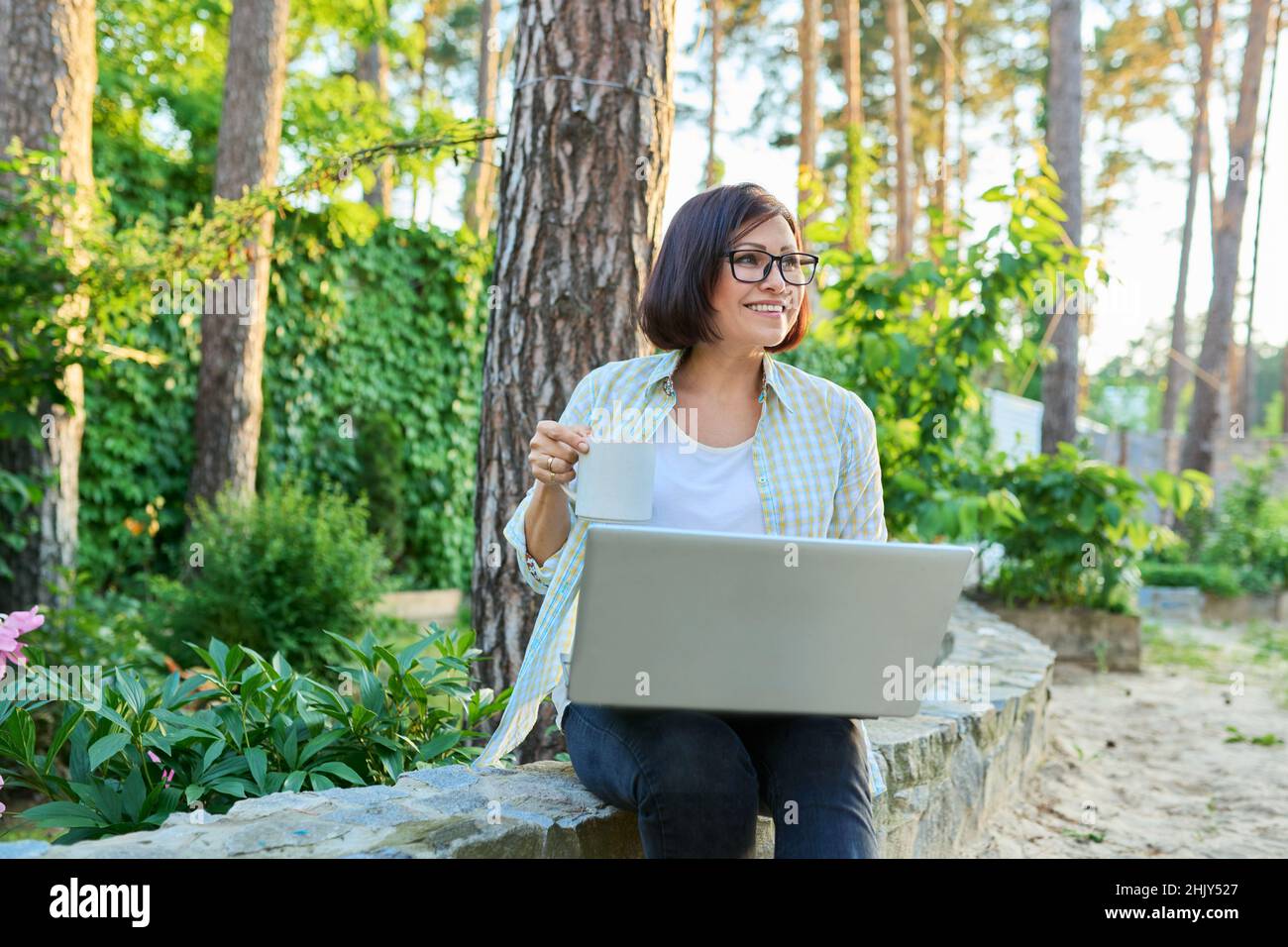 Middle age woman with laptop cup resting working in the backyard Stock ...