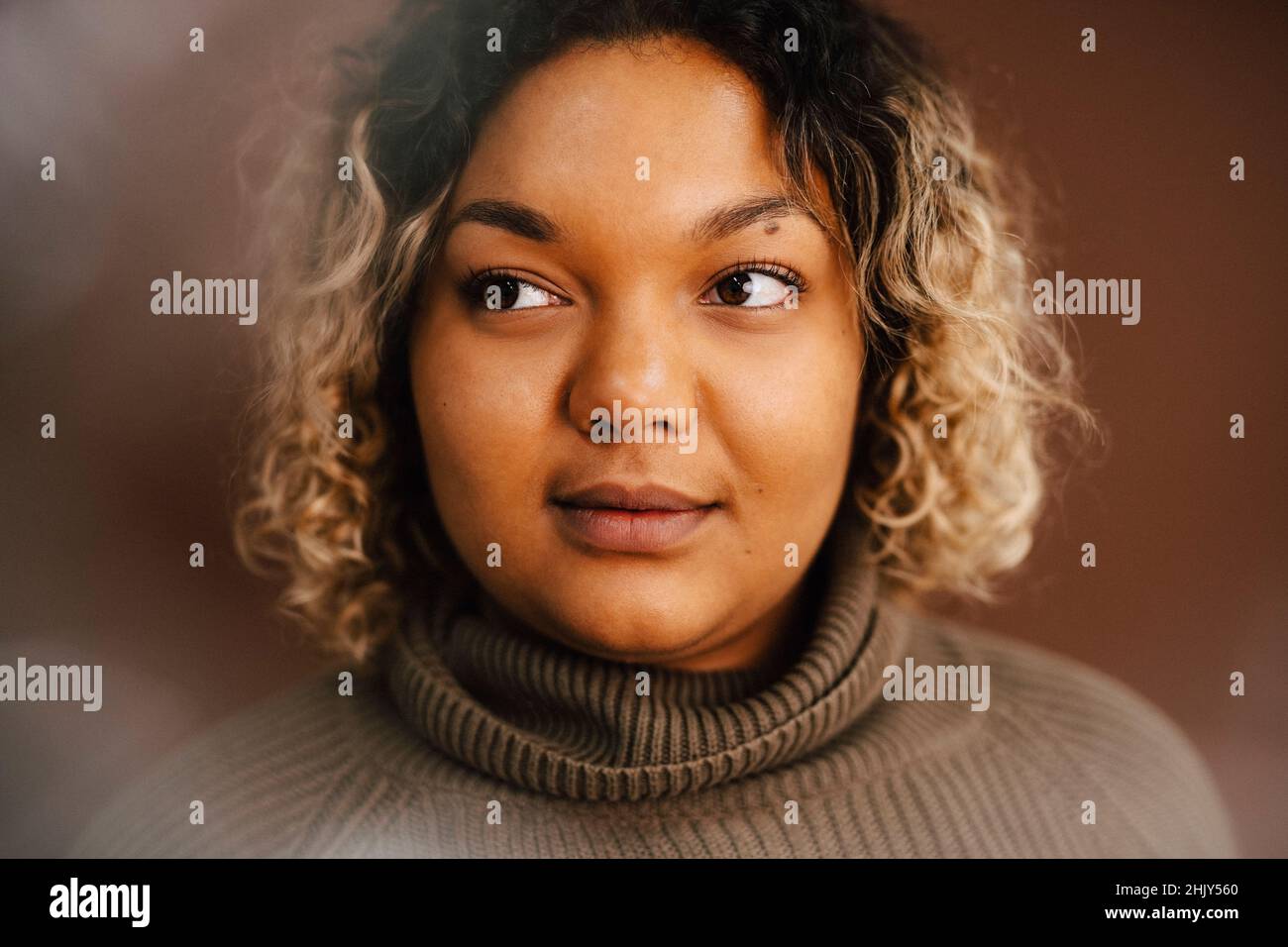 Contemplative woman over brown background in studio Stock Photo - Alamy