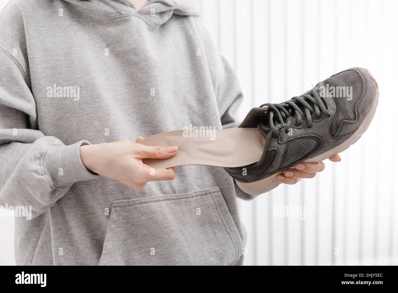 Woman putting orthopedic insole into shoe at home. Sports girl fitting ...