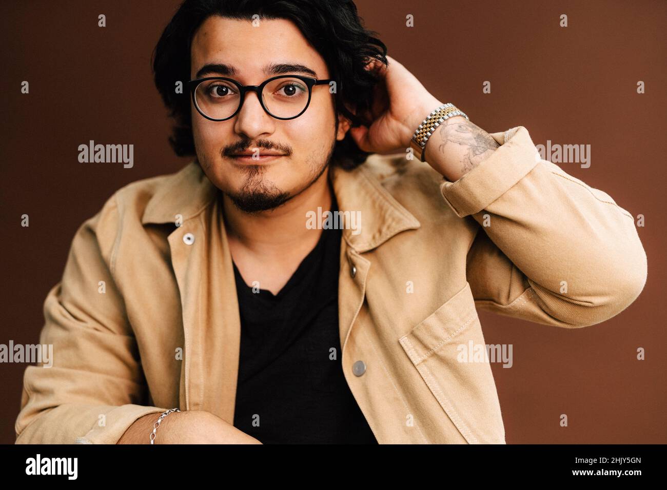 Portrait of man with hand in hair at studio Stock Photo - Alamy