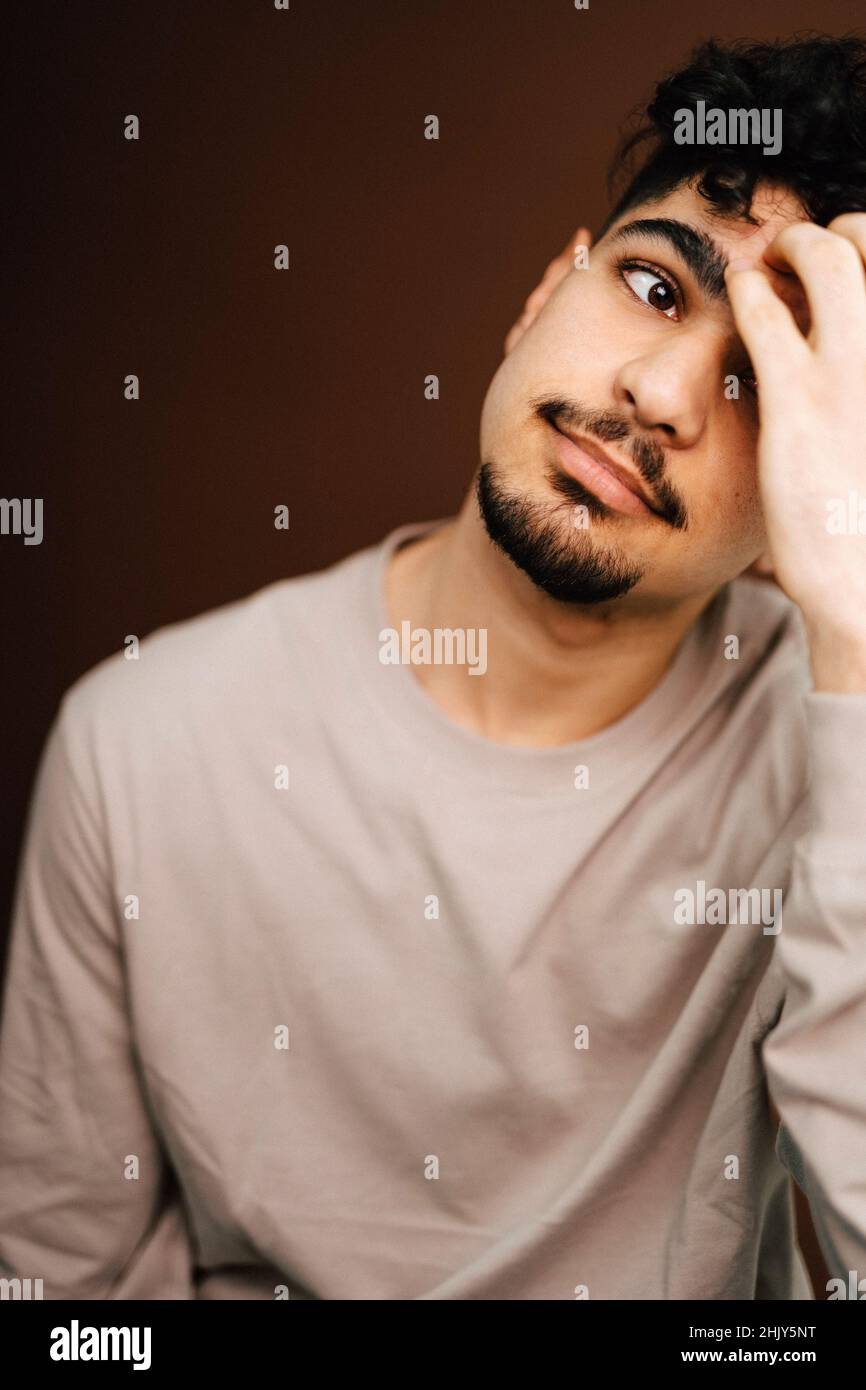 Tired man with head in hand against brown background Stock Photo - Alamy