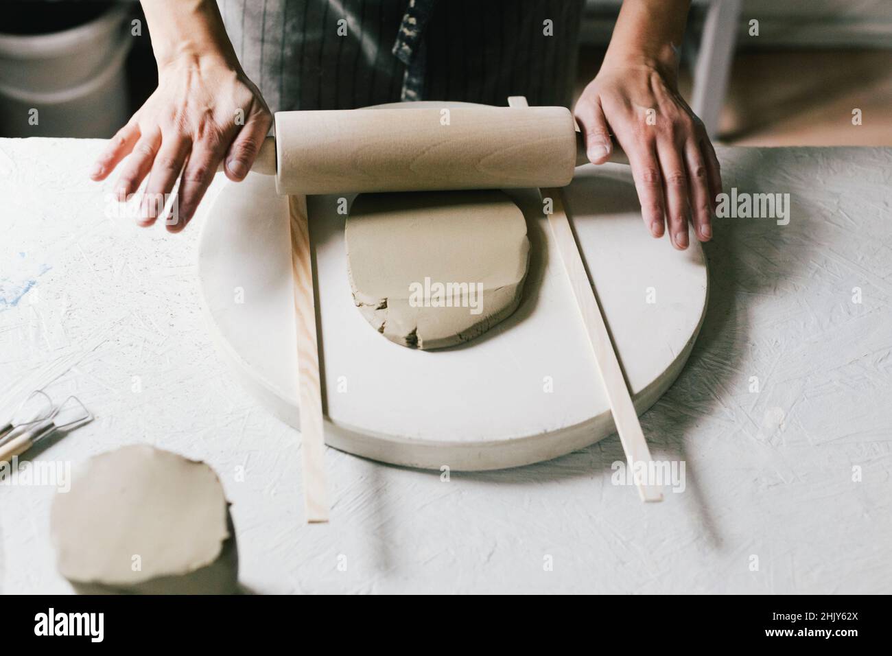 Female owner rolling clay at table in ceramics store Stock Photo - Alamy