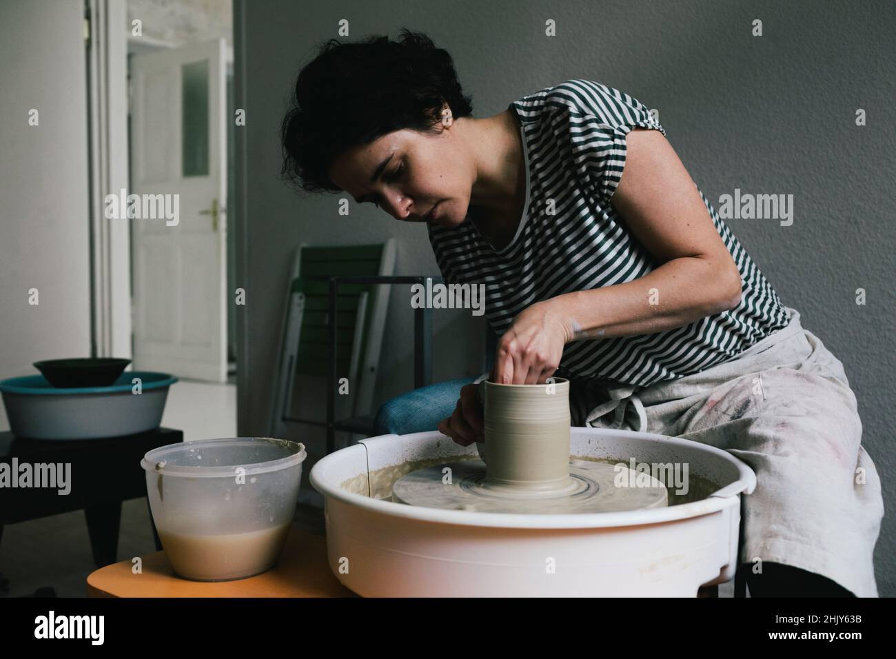 Female potter modeling shape to pot at ceramics workshop Stock Photo ...