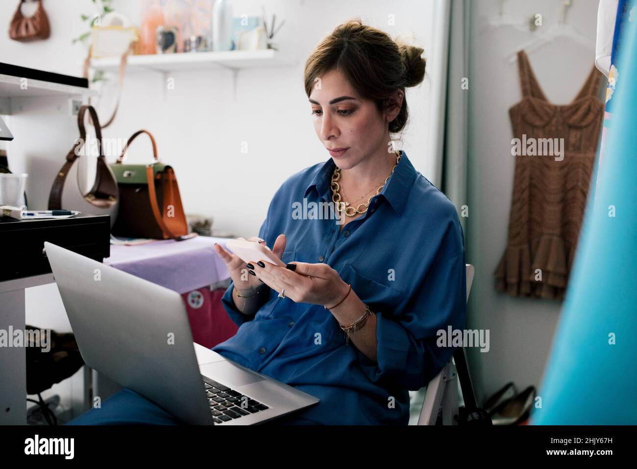 Female owner using smart phone while working in clothing store Stock ...