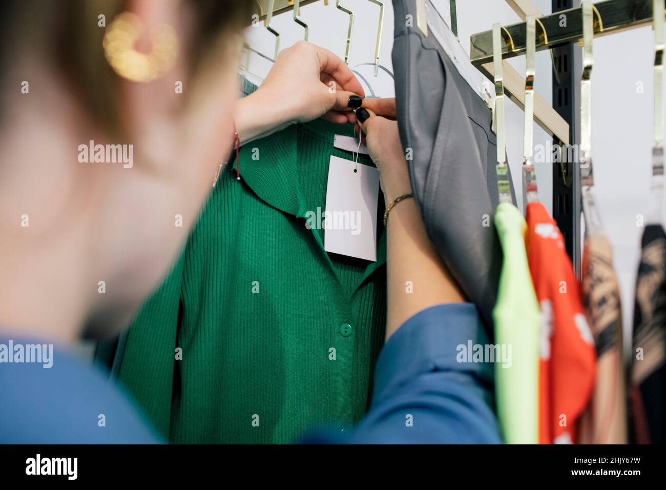 Female owner tying price tag on clothes in store Stock Photo - Alamy